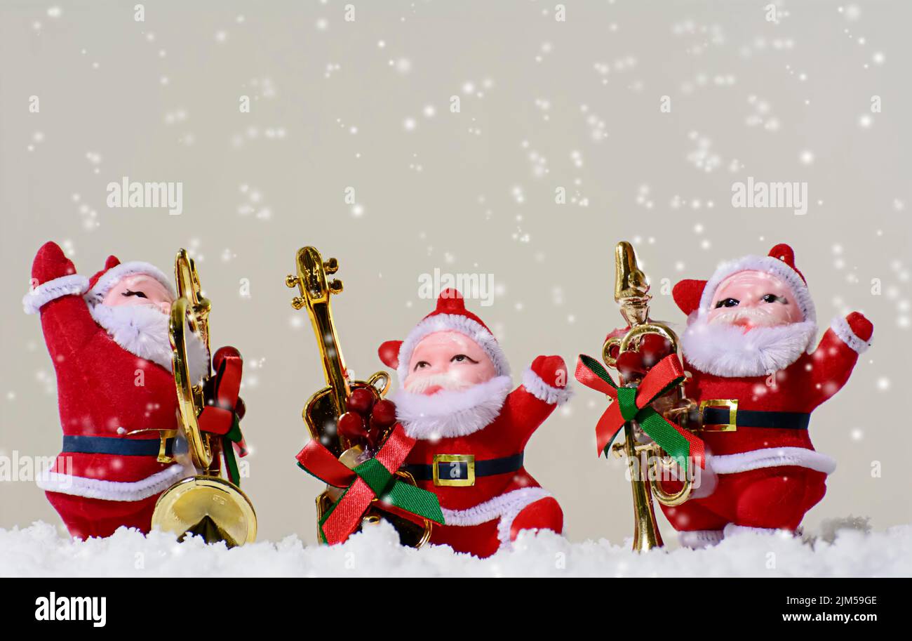 The snowflakes falling over three small figures of Santa Claus with ...