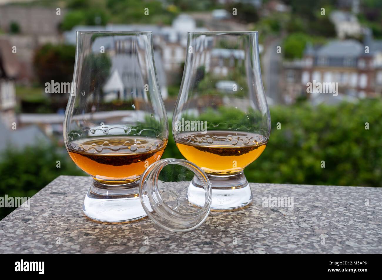Two drams of scotch whiskey with view on old houses on background ...