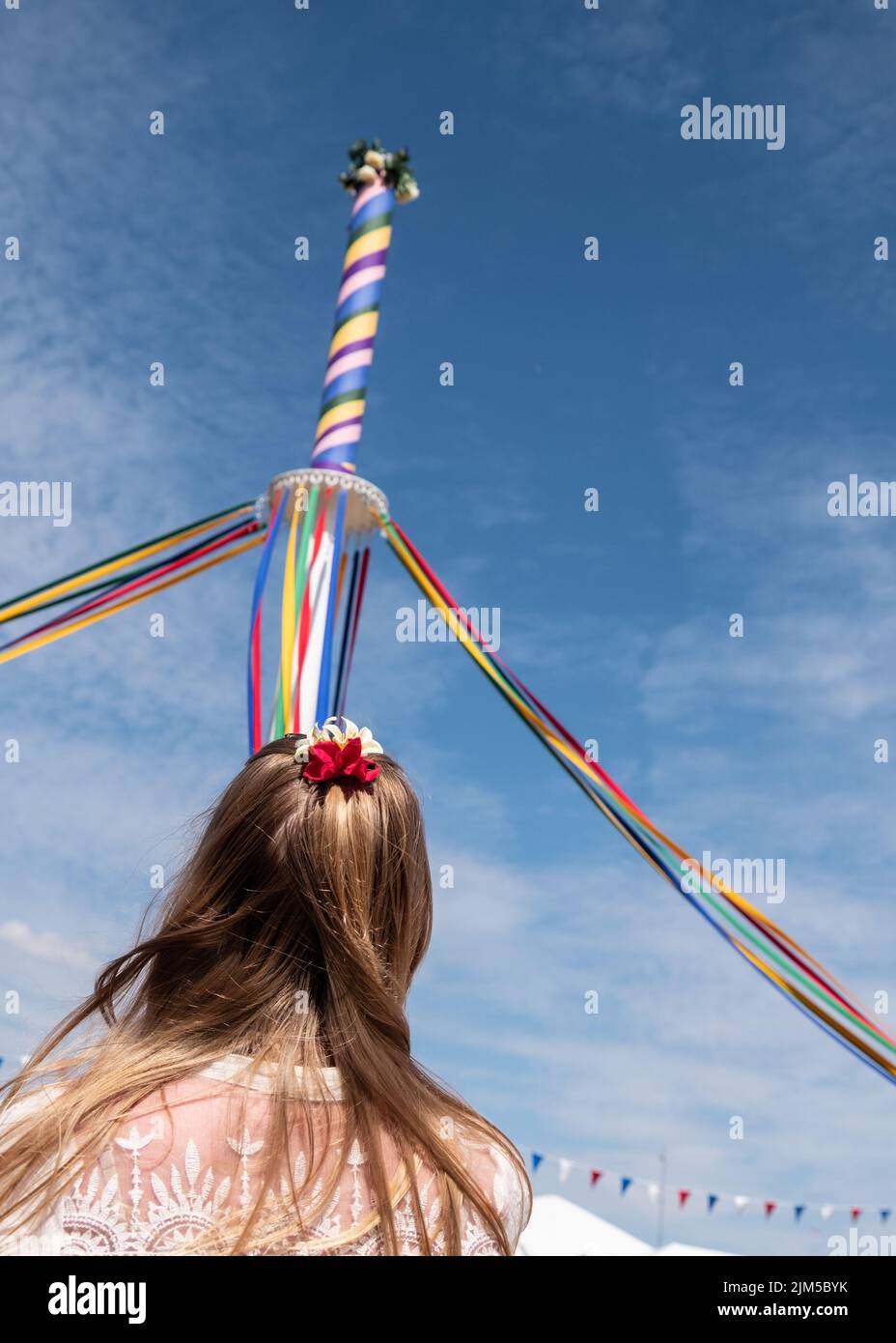 A young dancer looking at the pole with colored ribbons on a ...