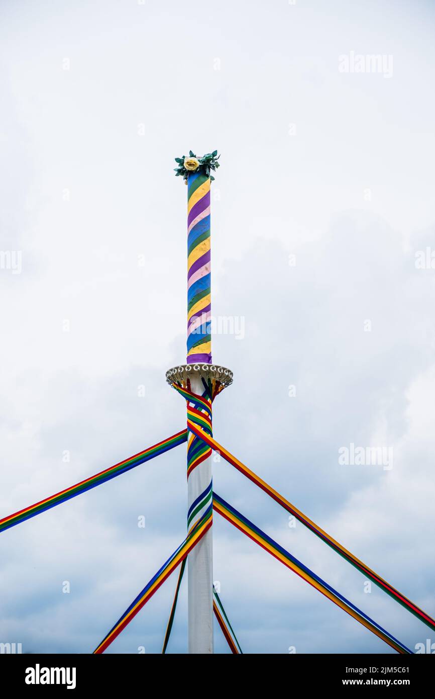 A vertical shot of a pole with colored ribbons and flowers on a ...