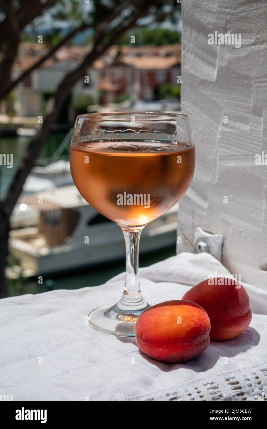 Drinking of cold rose wine from Provence with red apricots and view on yacht harbour of Port ...