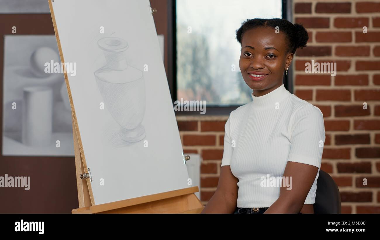 Portrait of creative woman sitting in front of canvas with drawing ...