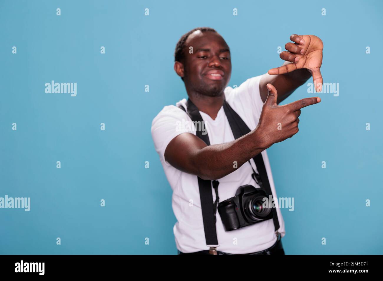 Young guy with DSLR device gesturing taking photo with hands. Confident ...