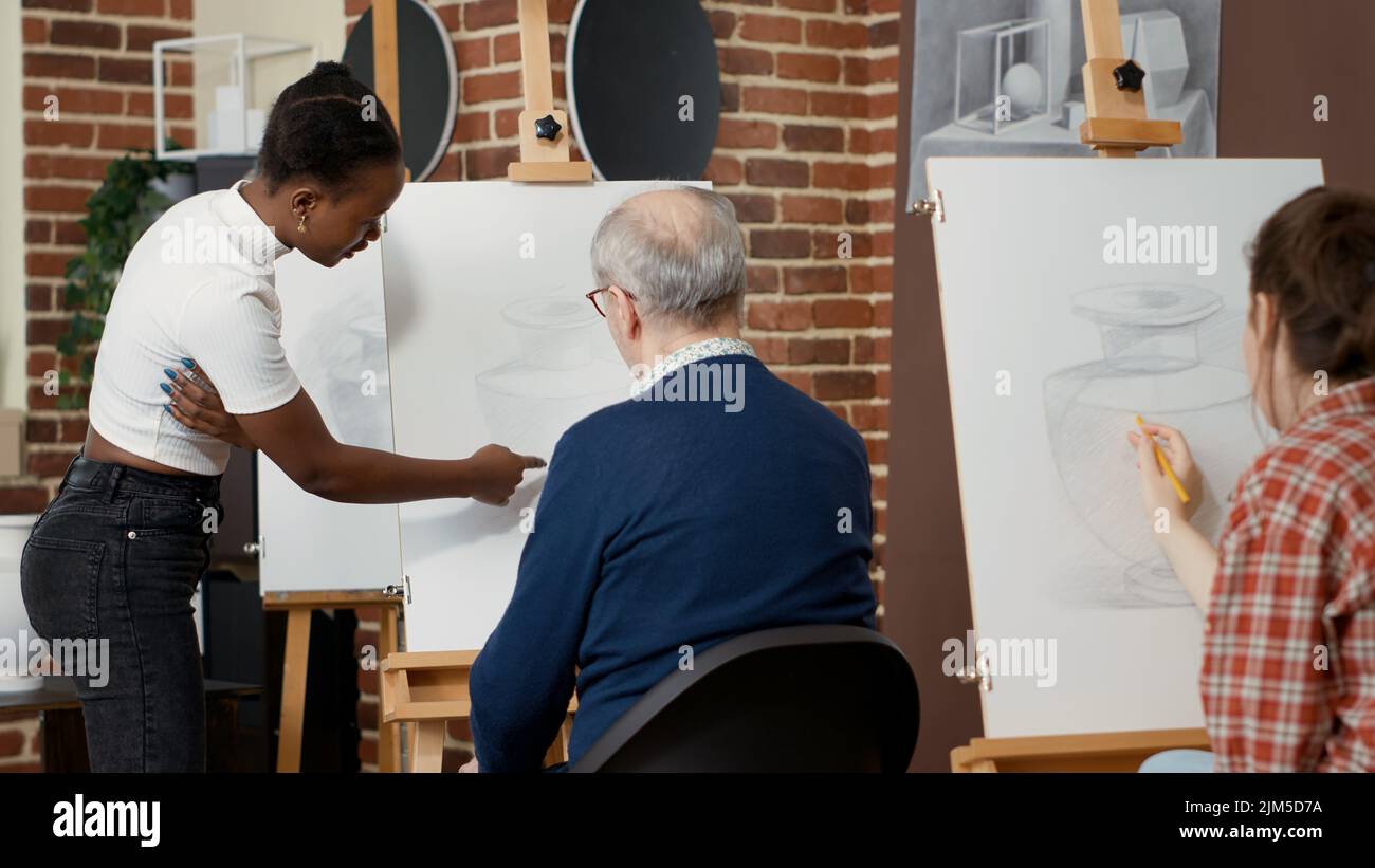 African american teacher explaining drawing technique to old student ...