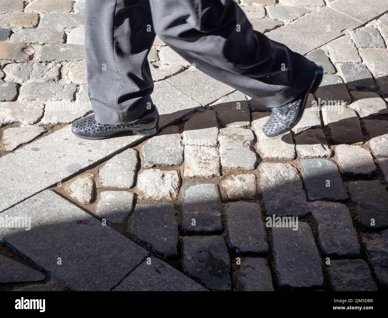 A closeup of the man walking on the cobblestone surface Stock Photo - Alamy