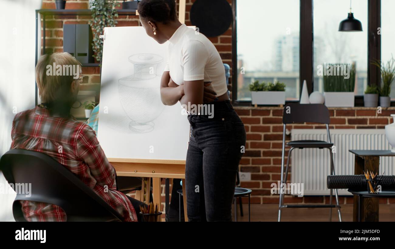 Art teacher training senior woman to draw artwork in art class program ...