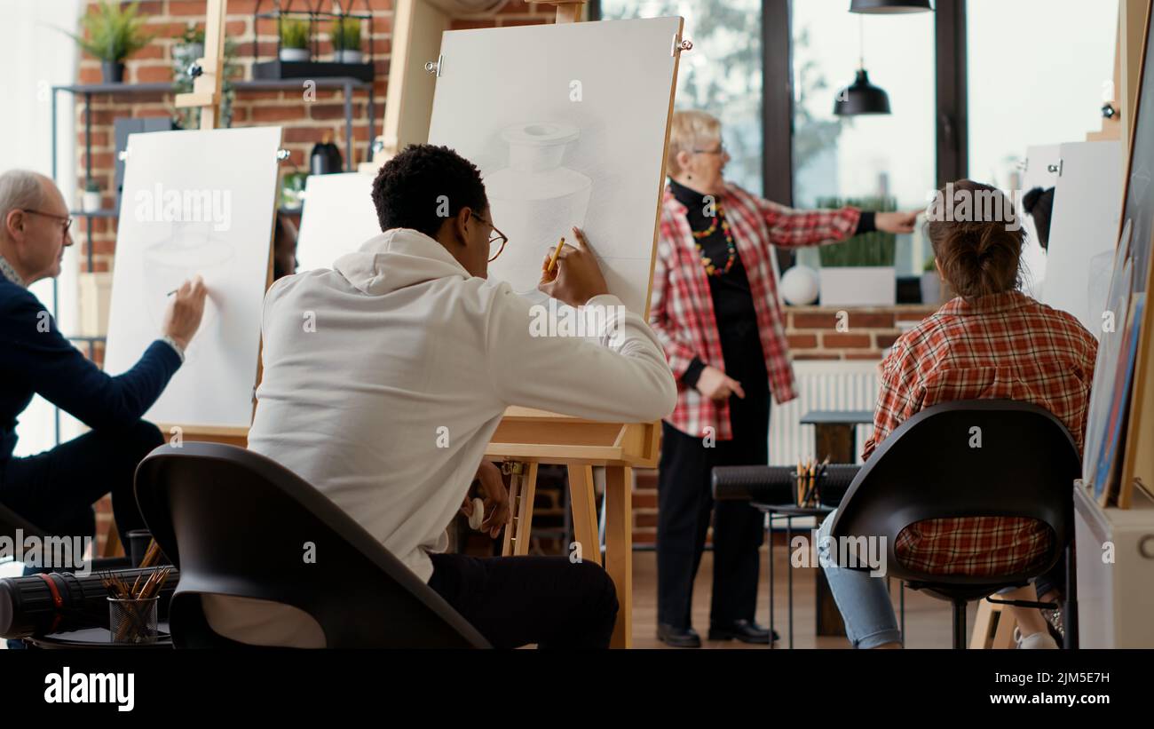African american student using pencil to draw vase sketch on canvas ...