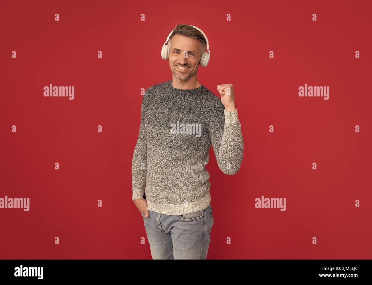 Happy man listen to music in headphones making winning gesture red ...