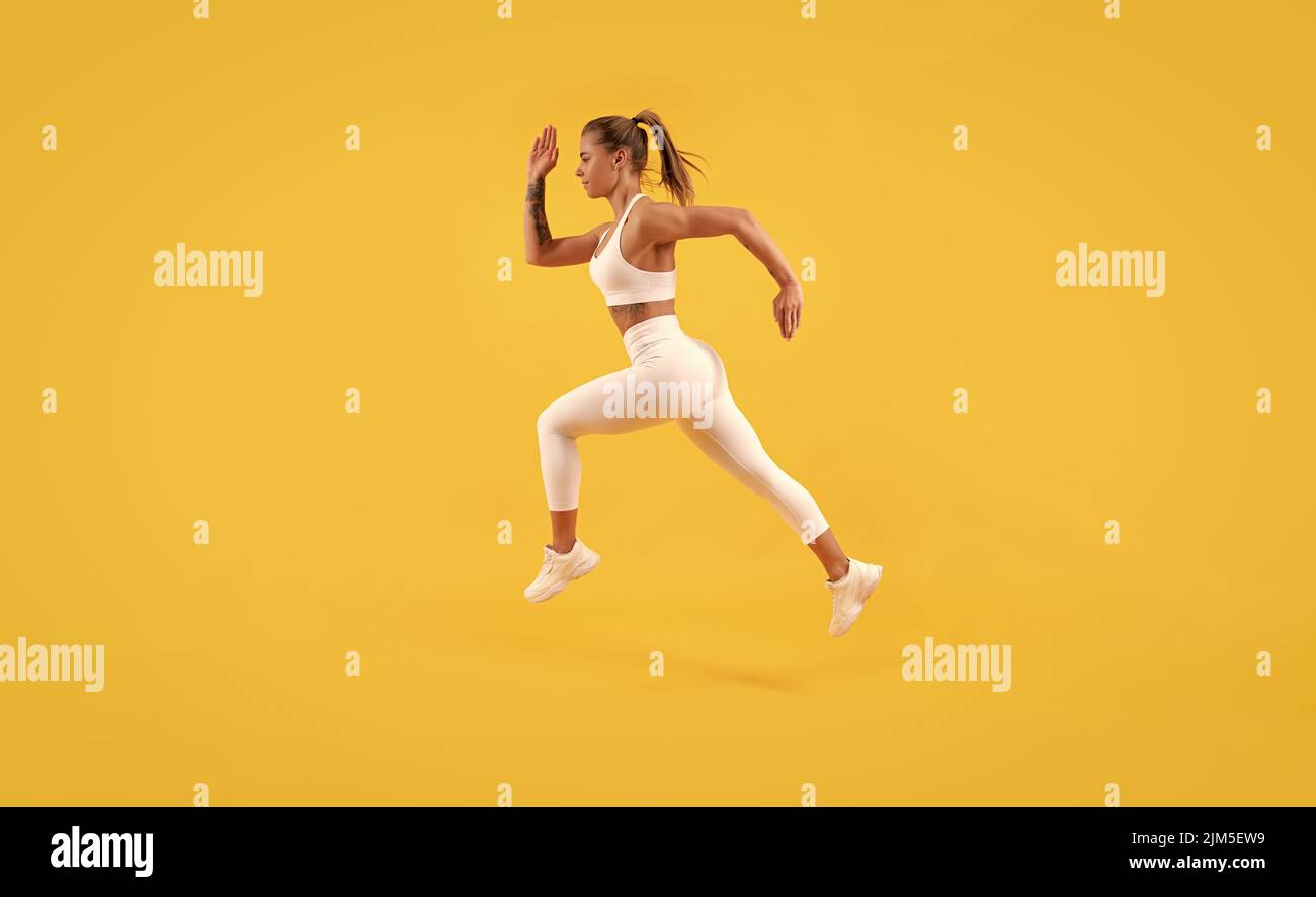 energetic fitness woman runner running on yellow background Stock Photo ...