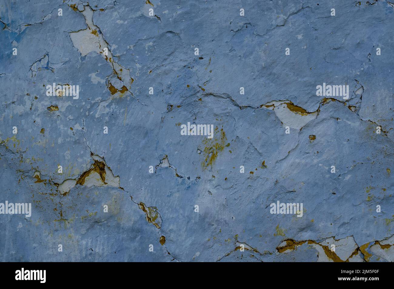 A close up shot of an old blue wall with cracks and paint chipping off ...