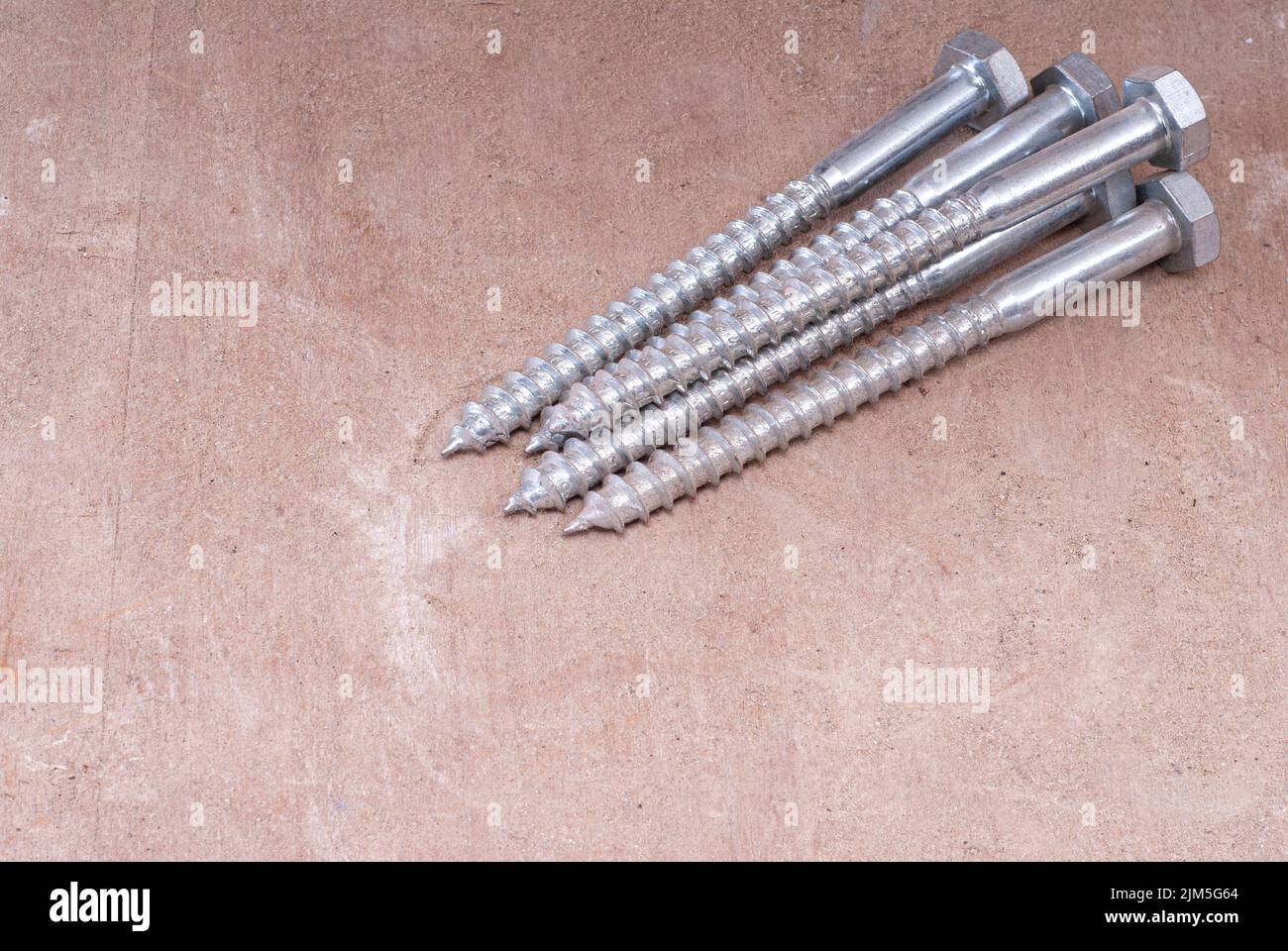 A pile of galvanized wood screws on a textured brown background Stock ...