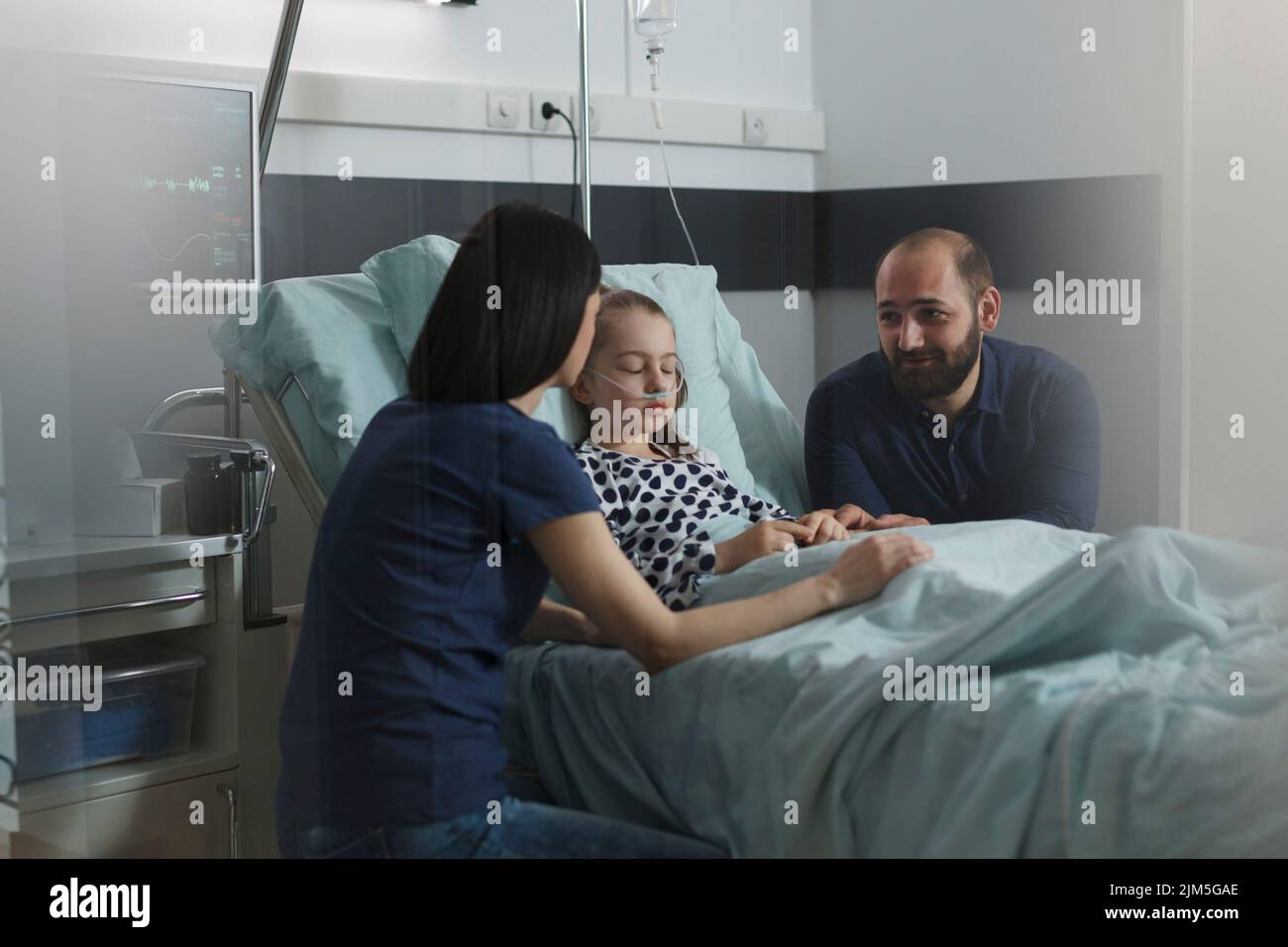 Considerate parents sitting beside hospitalized sick little daughter ...