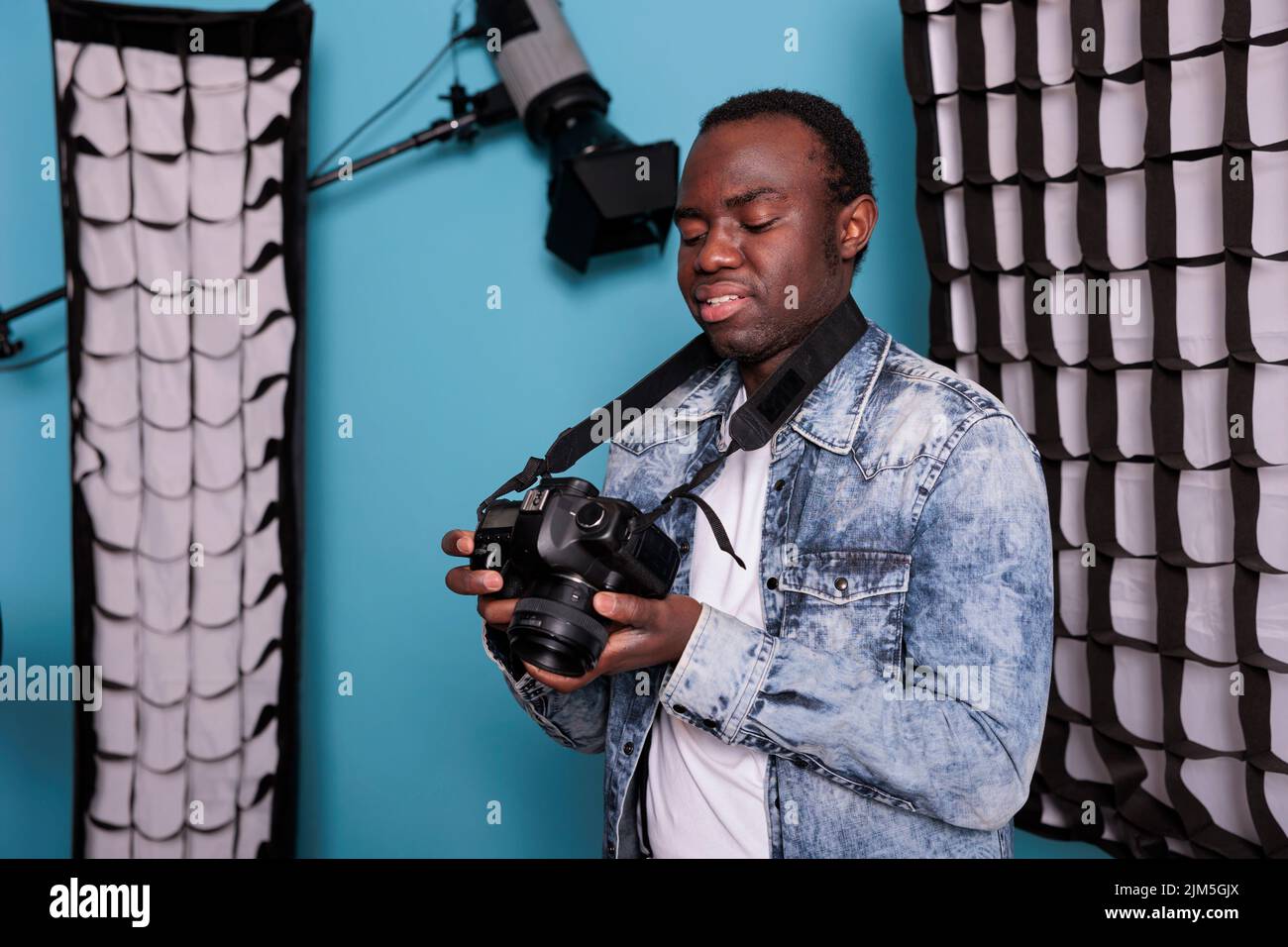 Happy photography enthusiast with DSLR device standing on blue ...