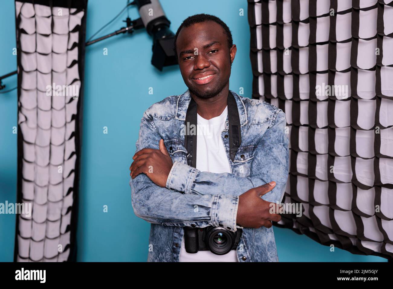 Producer standing beside professional photo equipment with arms crossed ...