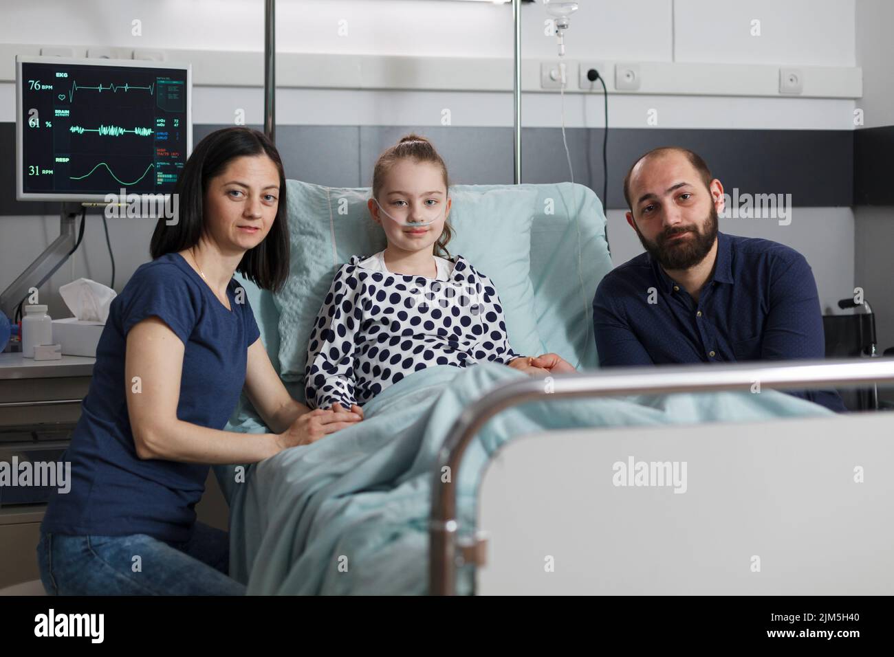 Portrait shot of caring parents sitting beside hospitalized sick ...