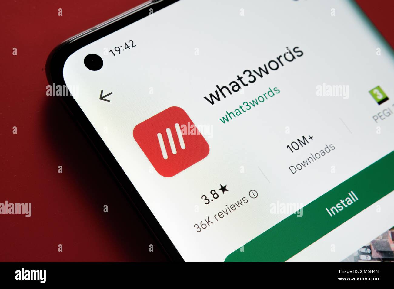 what3words app seen in Google Play Store on the smartphone screen placed on red background ...