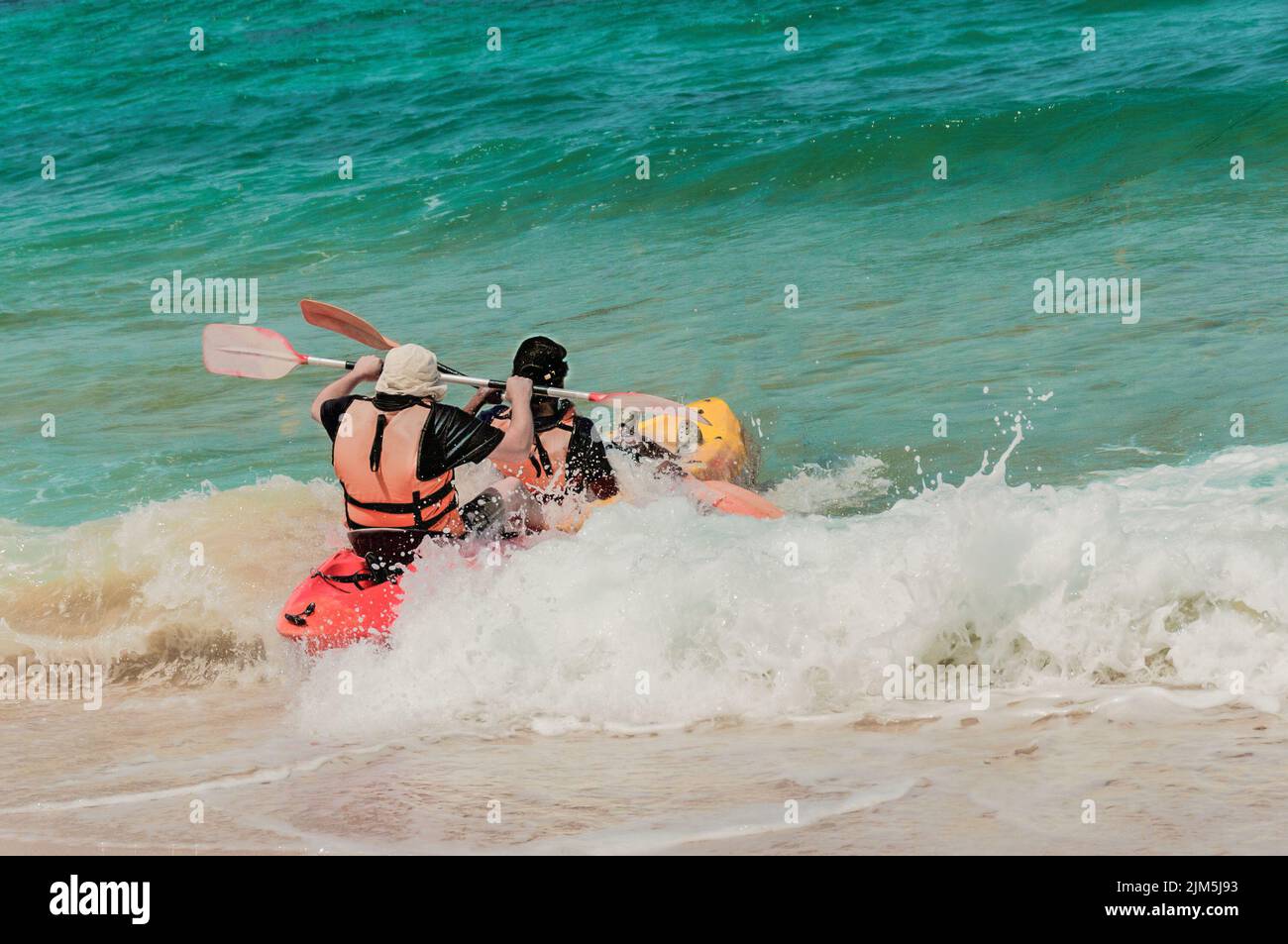 Two athletes compete in a kayak with sea waves, trying to swim away ...