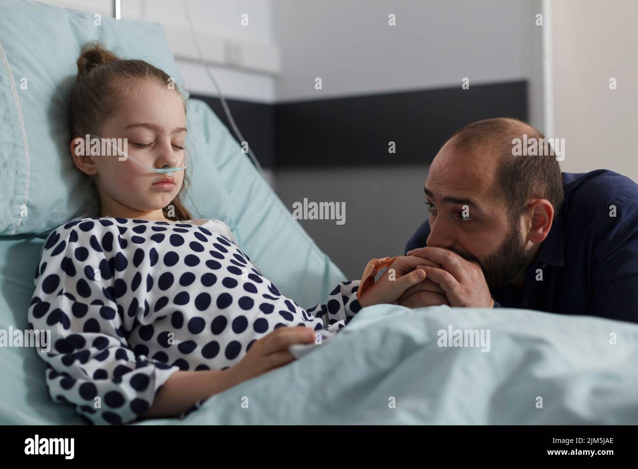Unwell sick kid sleeping while uneasy parent sitting beside her inside ...