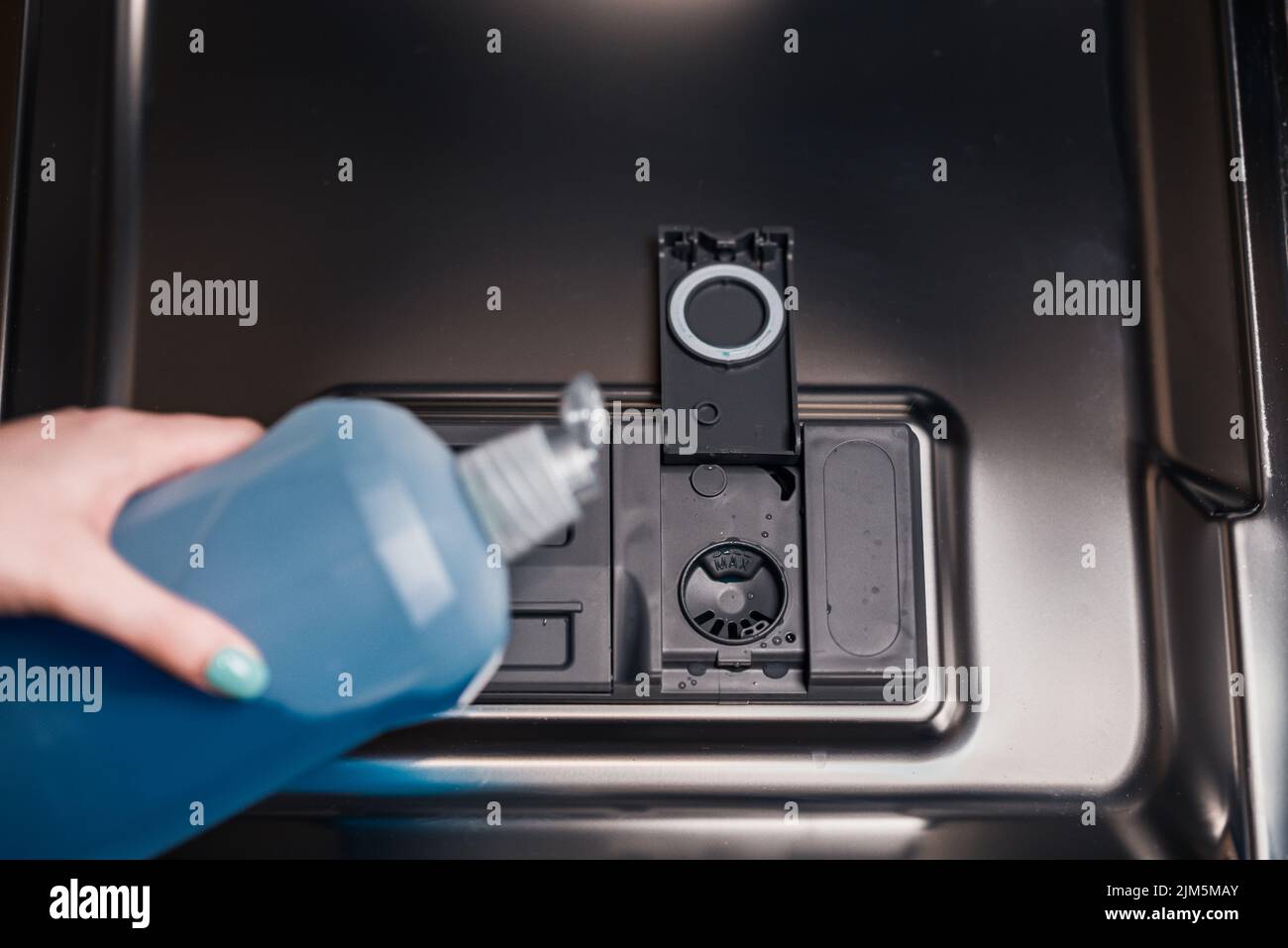 A closeup of a female hand pouring detergent into a dishwasher ...