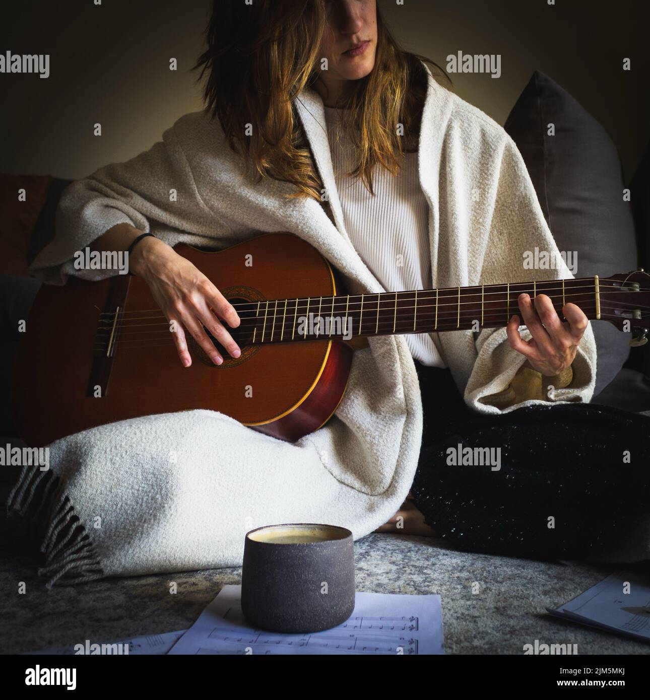A girl playing the guitar while drinking her coffee in the early ...
