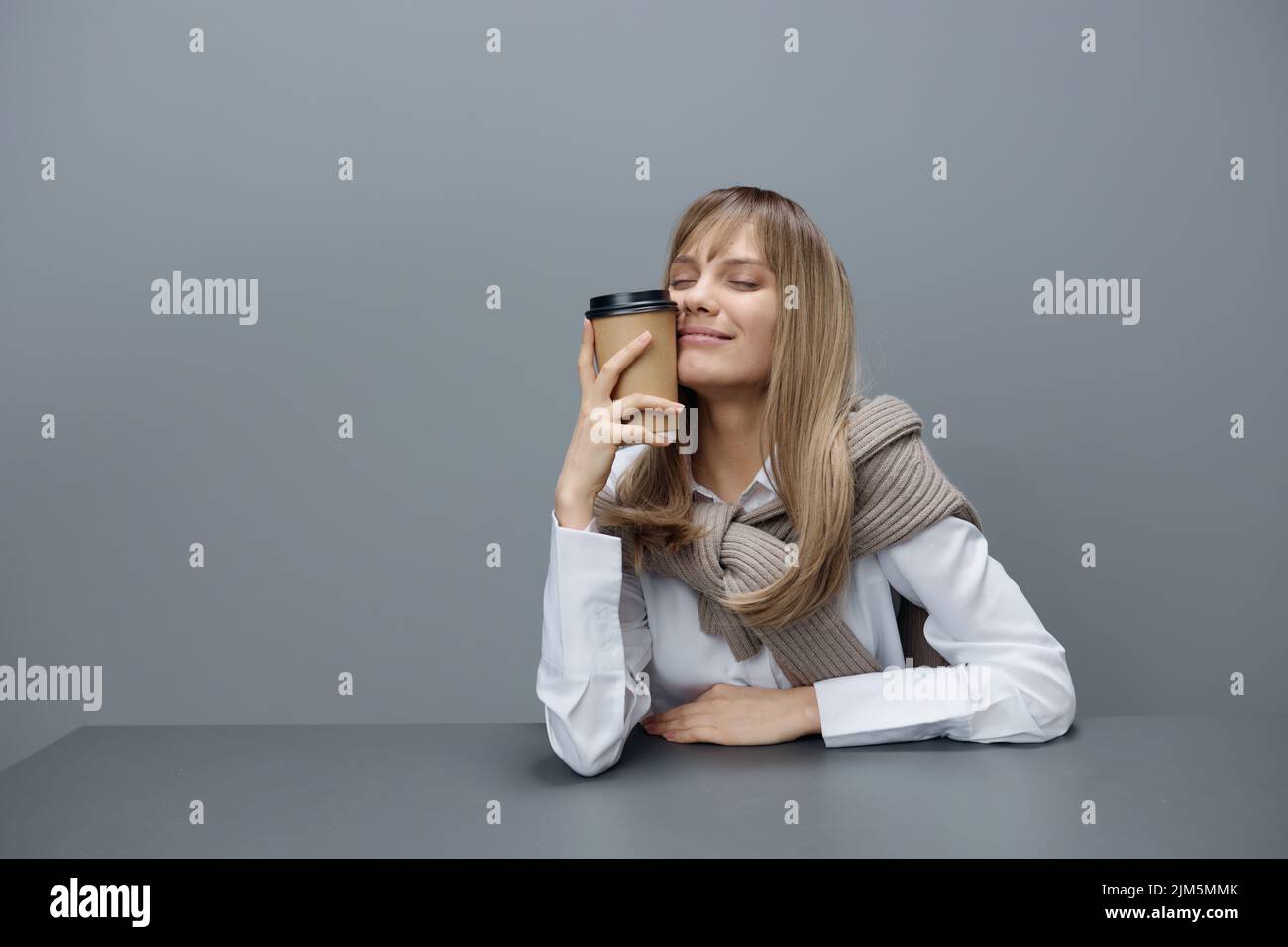 Cute happy young blonde student lady freelancer in warm sweater hug ...