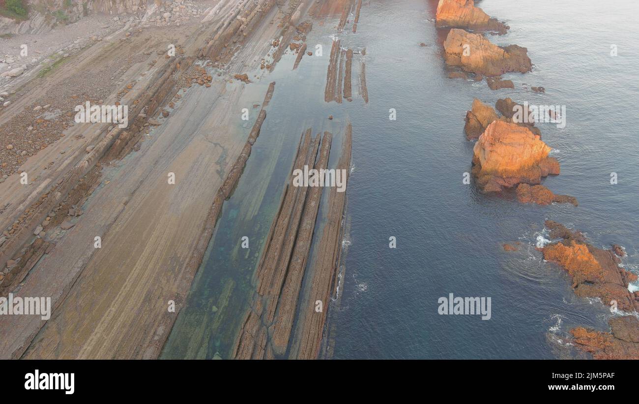 An aerial view of huge stones in the ocean and rocky shore on the side ...