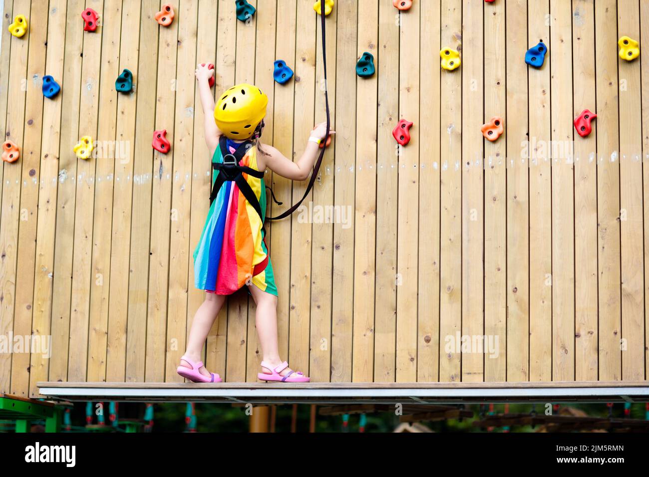 Child in forest adventure park. Kids climb on high rope trail. Agility ...