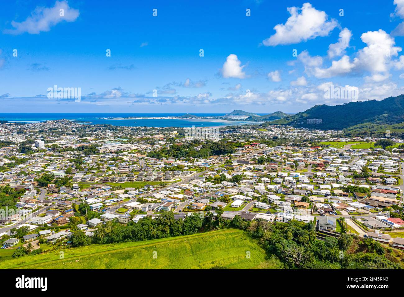An aerial view of a town in green forests by the sea in Oahu, Hawaii ...