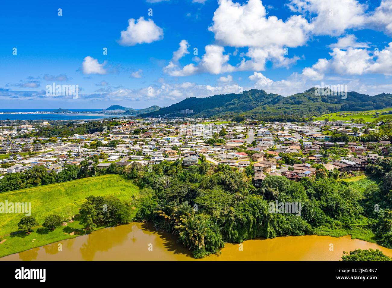 An aerial view of a town in green forests by the mountain and sea in ...