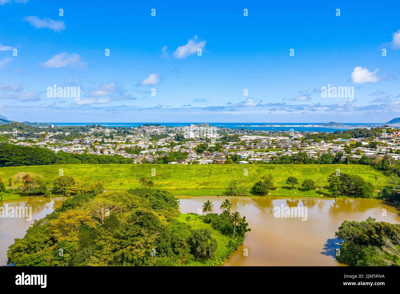 An aerial view of a town in green forests by the sea in Oahu, Hawaii ...