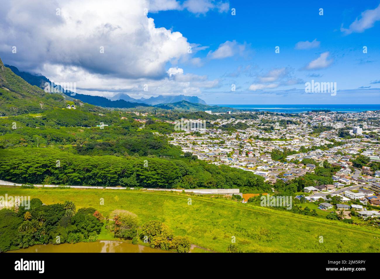 An aerial view of a town in green forests by the mountain in Oahu ...