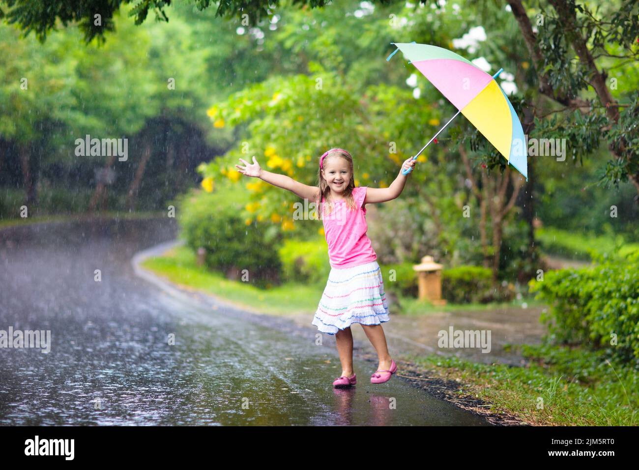 Kid playing out in the rain. Children with umbrella play outdoors in ...