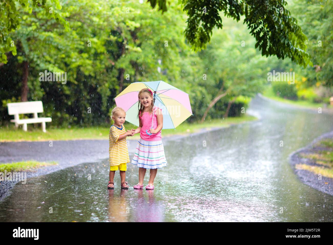 Kids playing out in the rain. Children with umbrella play outdoors in ...