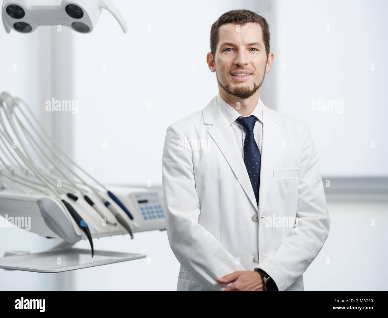 Closeup portrait of smiling male dentist in white lab coat looking at ...