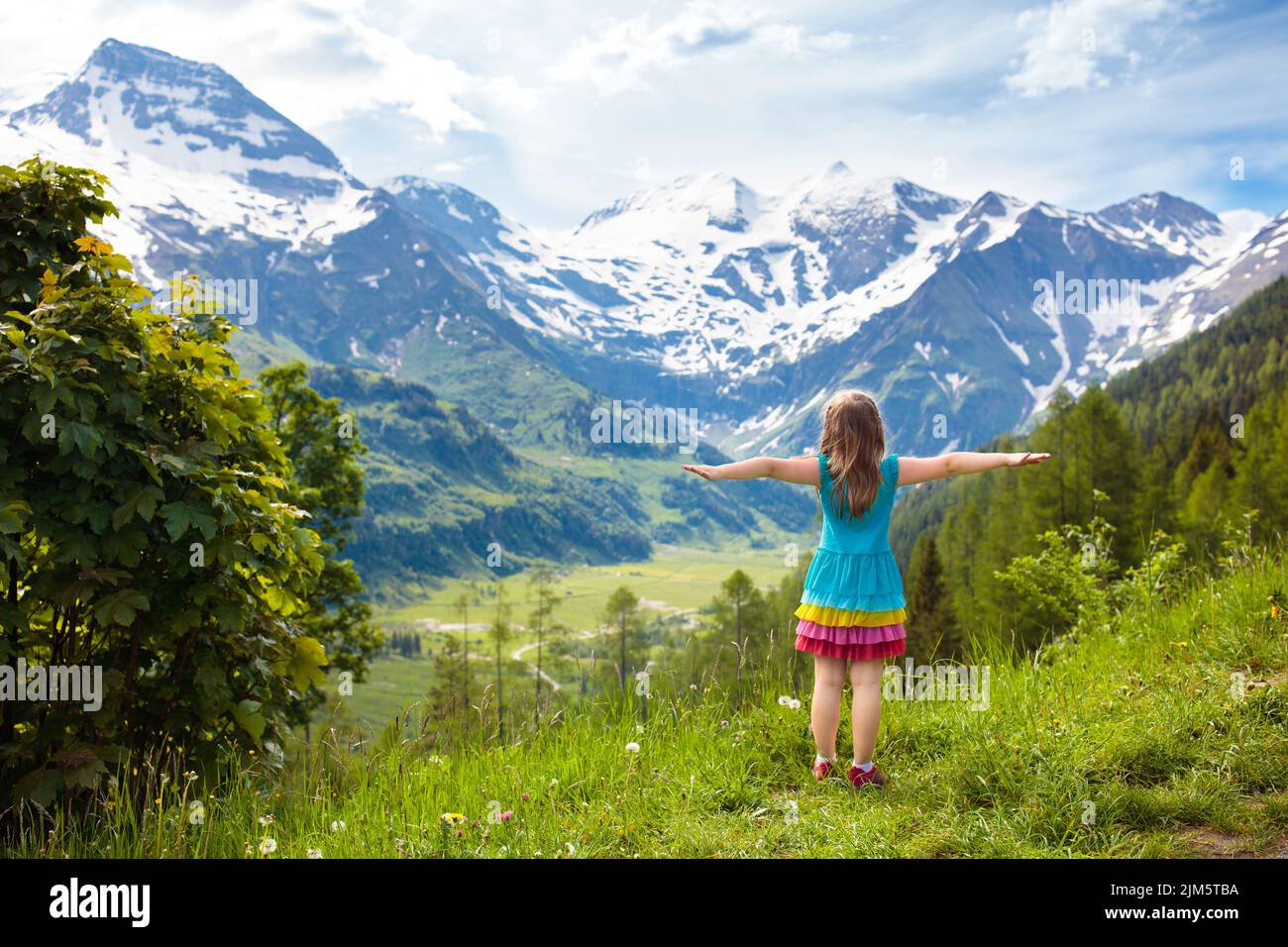 Children hiking in Alps mountains. Kids look at snow covered mountain ...