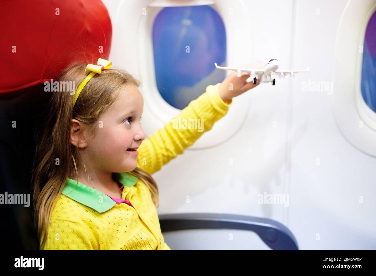 Child in airplane. Kid in air plane sitting in window seat. Flight ...