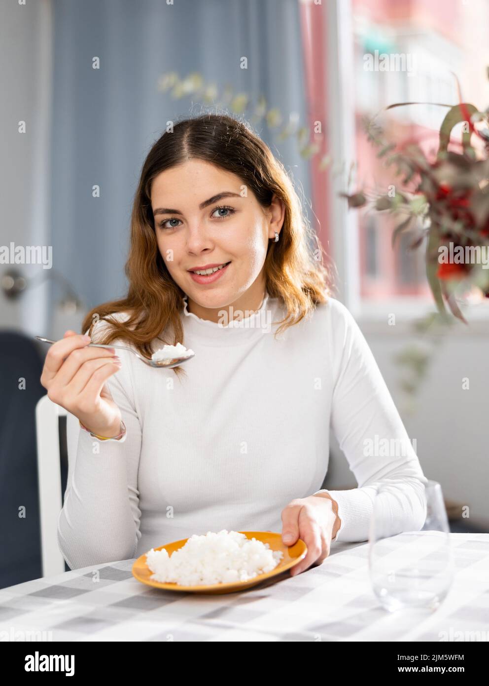 Emotional young woman eating rice at home Stock Photo - Alamy