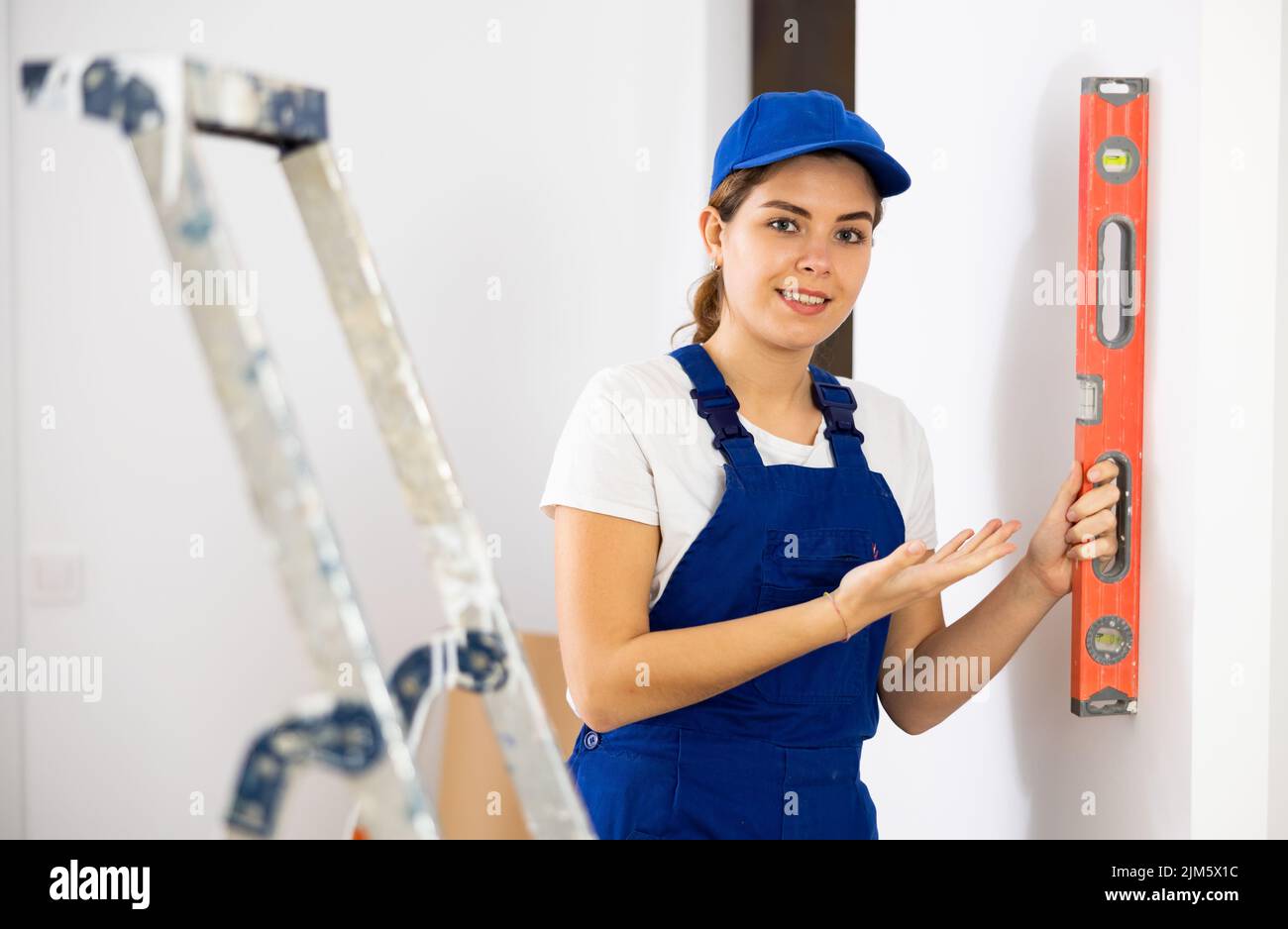 Woman builder using building level measures the vertical of wall Stock ...