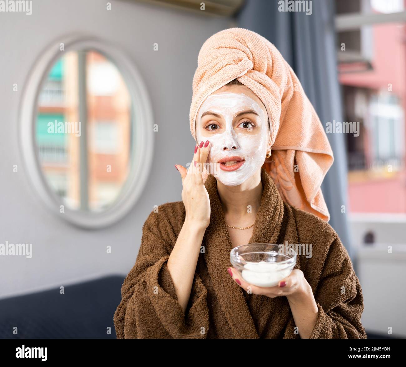 Happy woman taking care of face skin with lotion Stock Photo - Alamy