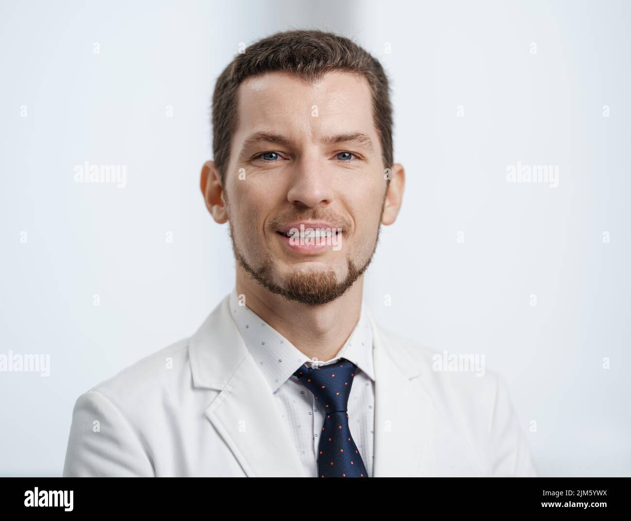 Closeup portrait of smiling male dentist in white lab coat looking at ...