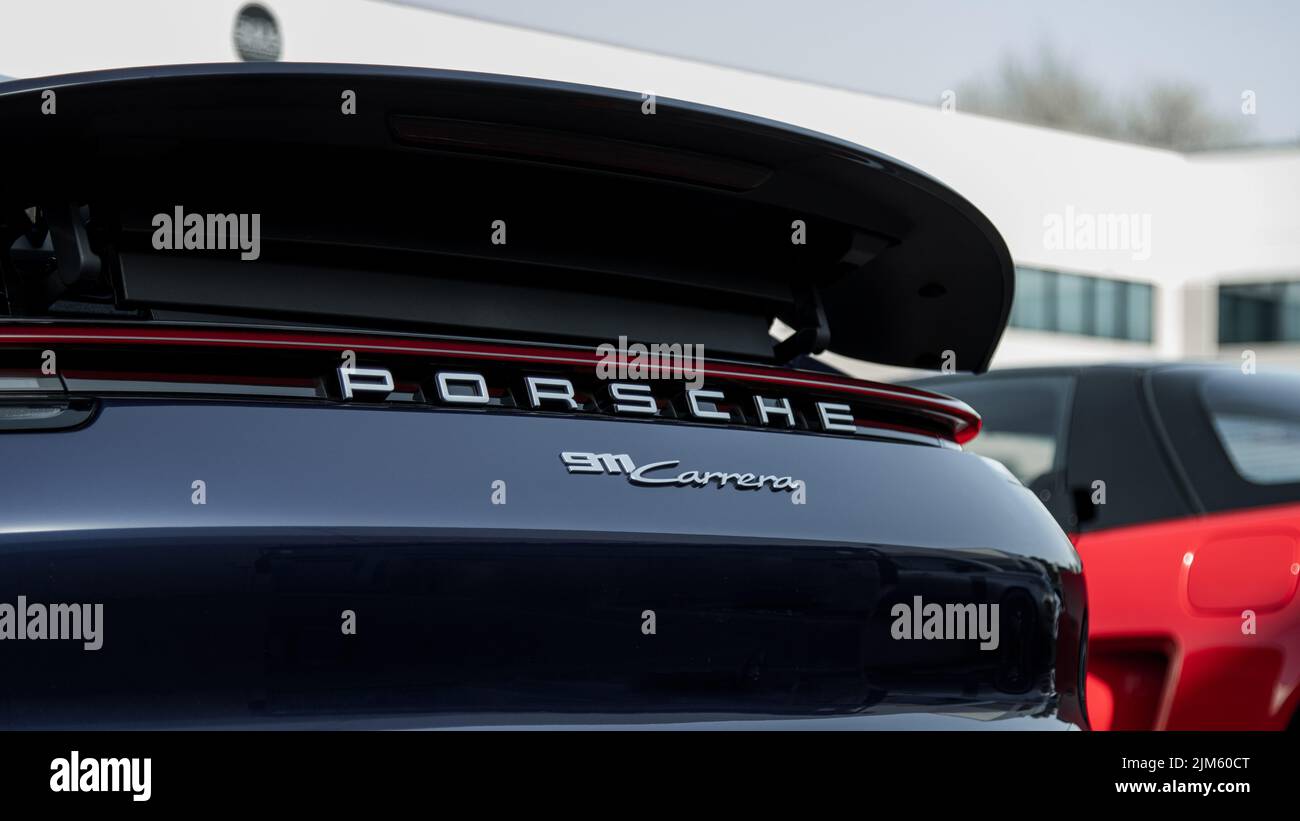 Blue Porsche 911 cabriolet rear end parked outside next to a red Acura ...