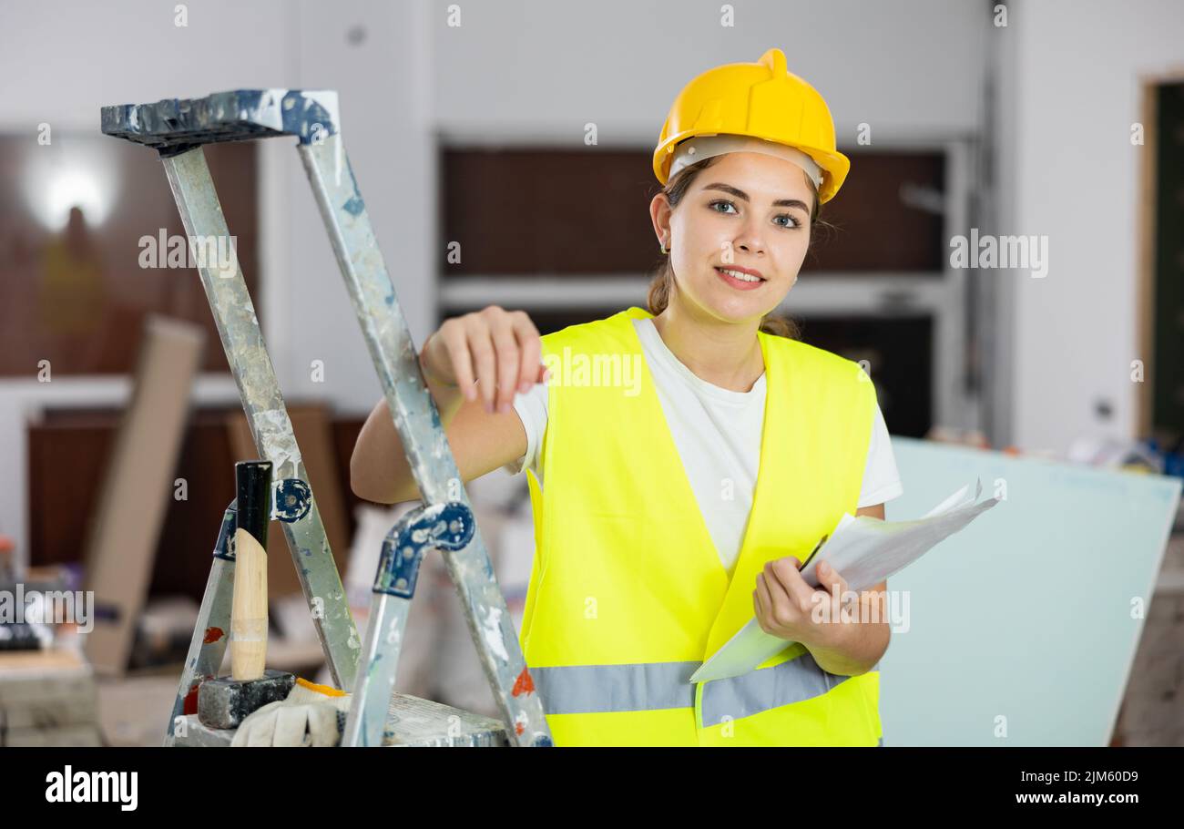 Positive female civil engineer taking notes while checking construction ...