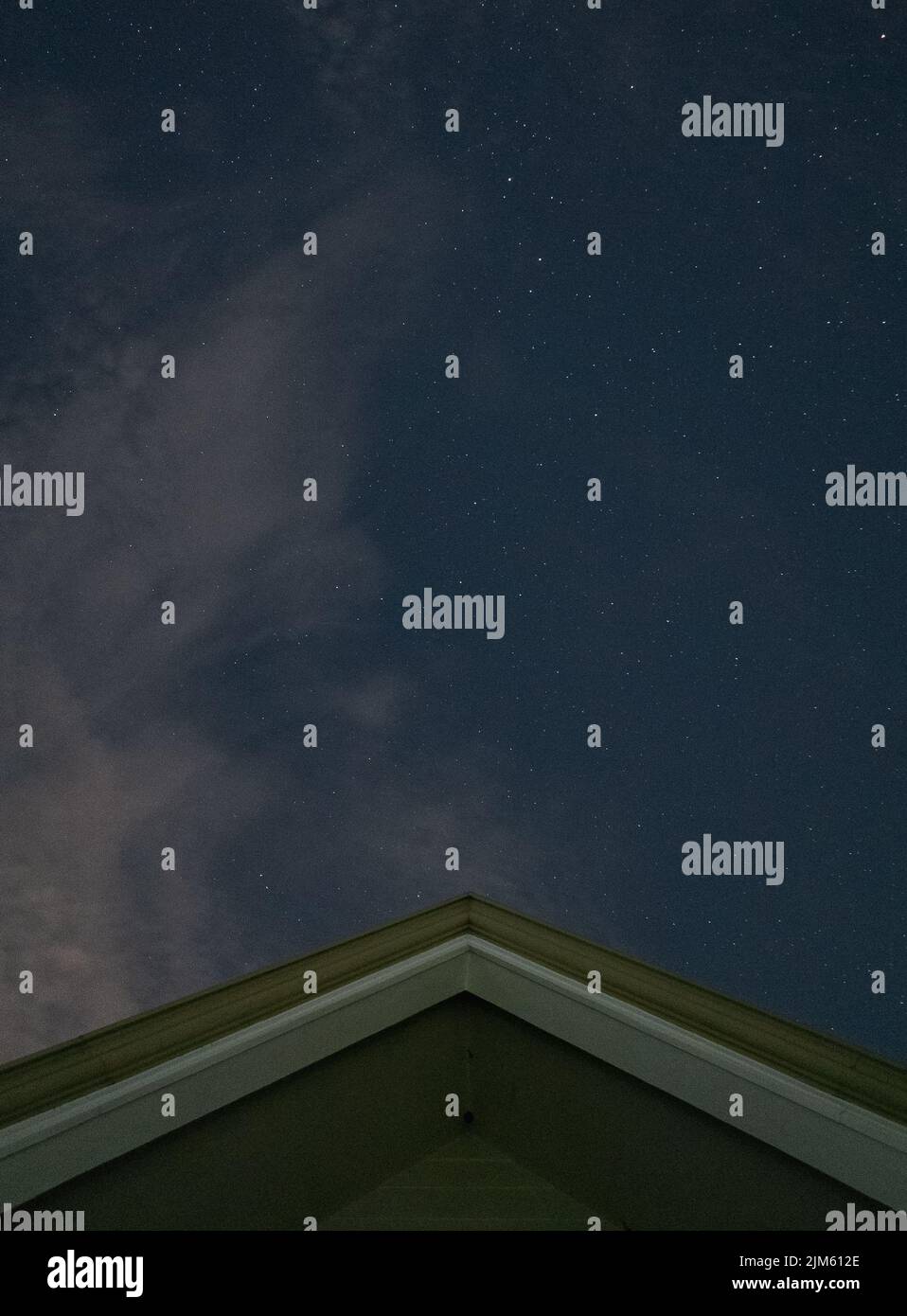 A vertical low angle shot of a building roof on dramatic starry sky background Stock Photo - Alamy