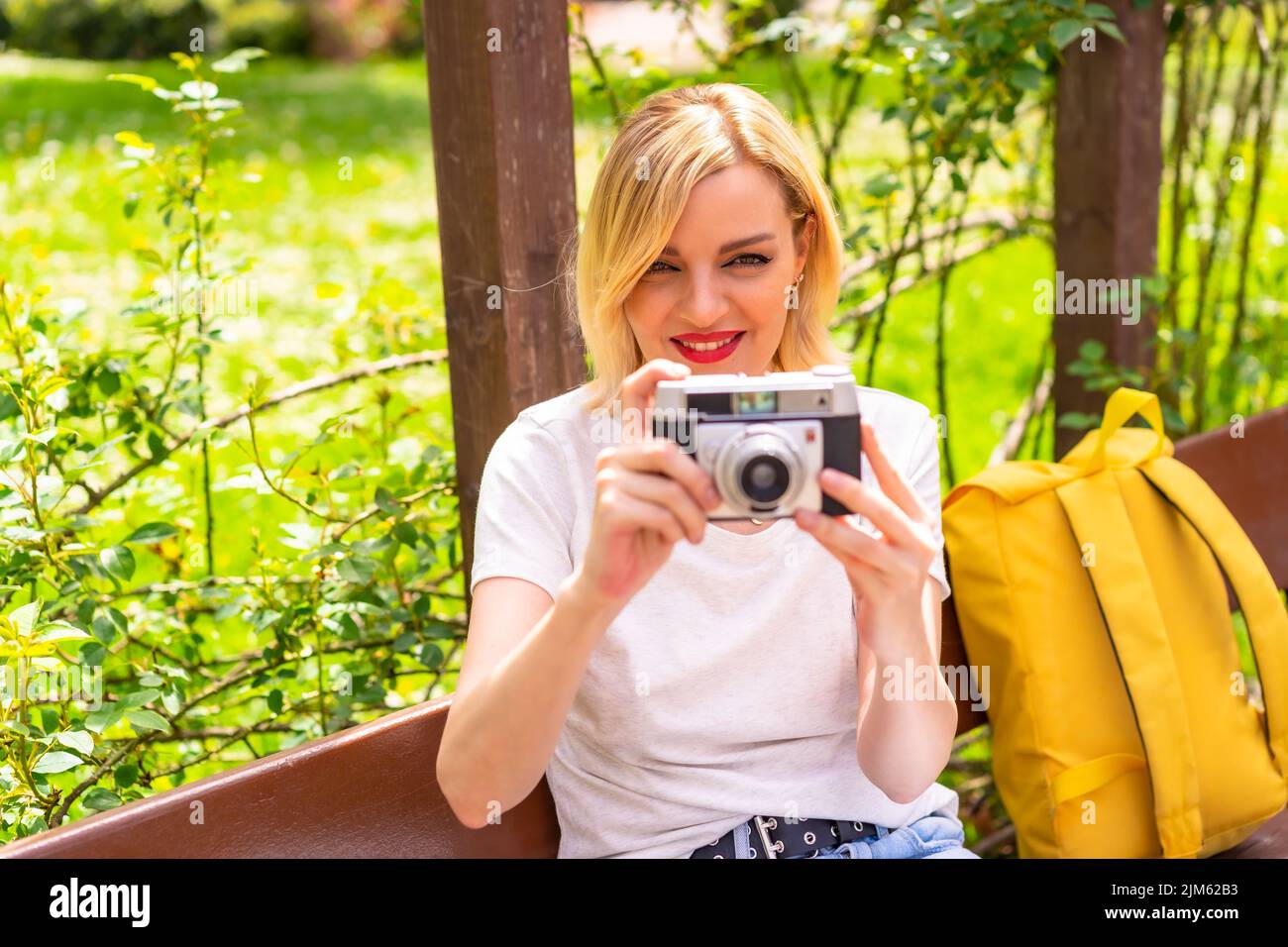 A blonde Caucasian girl looking at the photos in the camera while ...