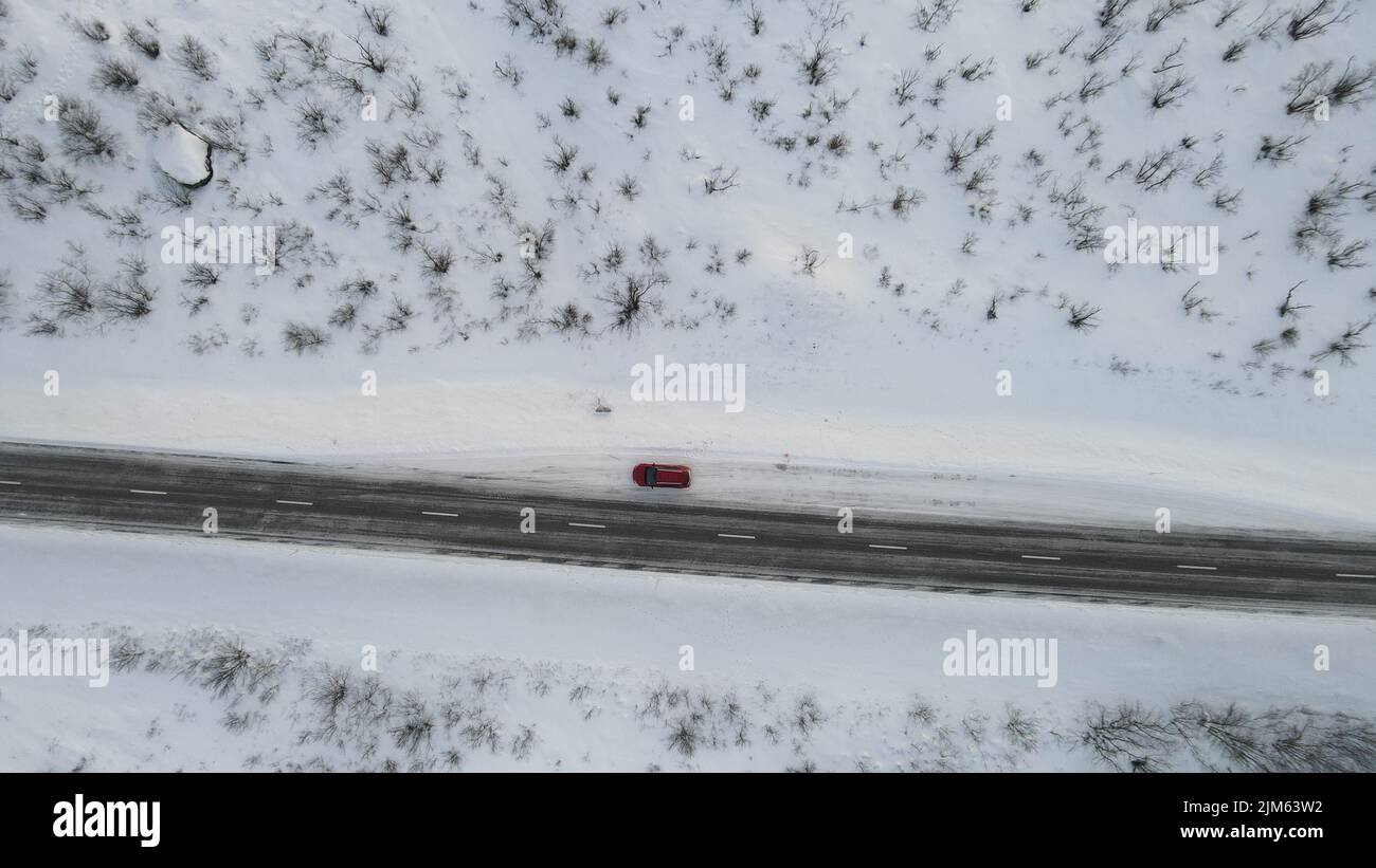 An aerial view of a vehicle on an asphalt road cutting through fields ...