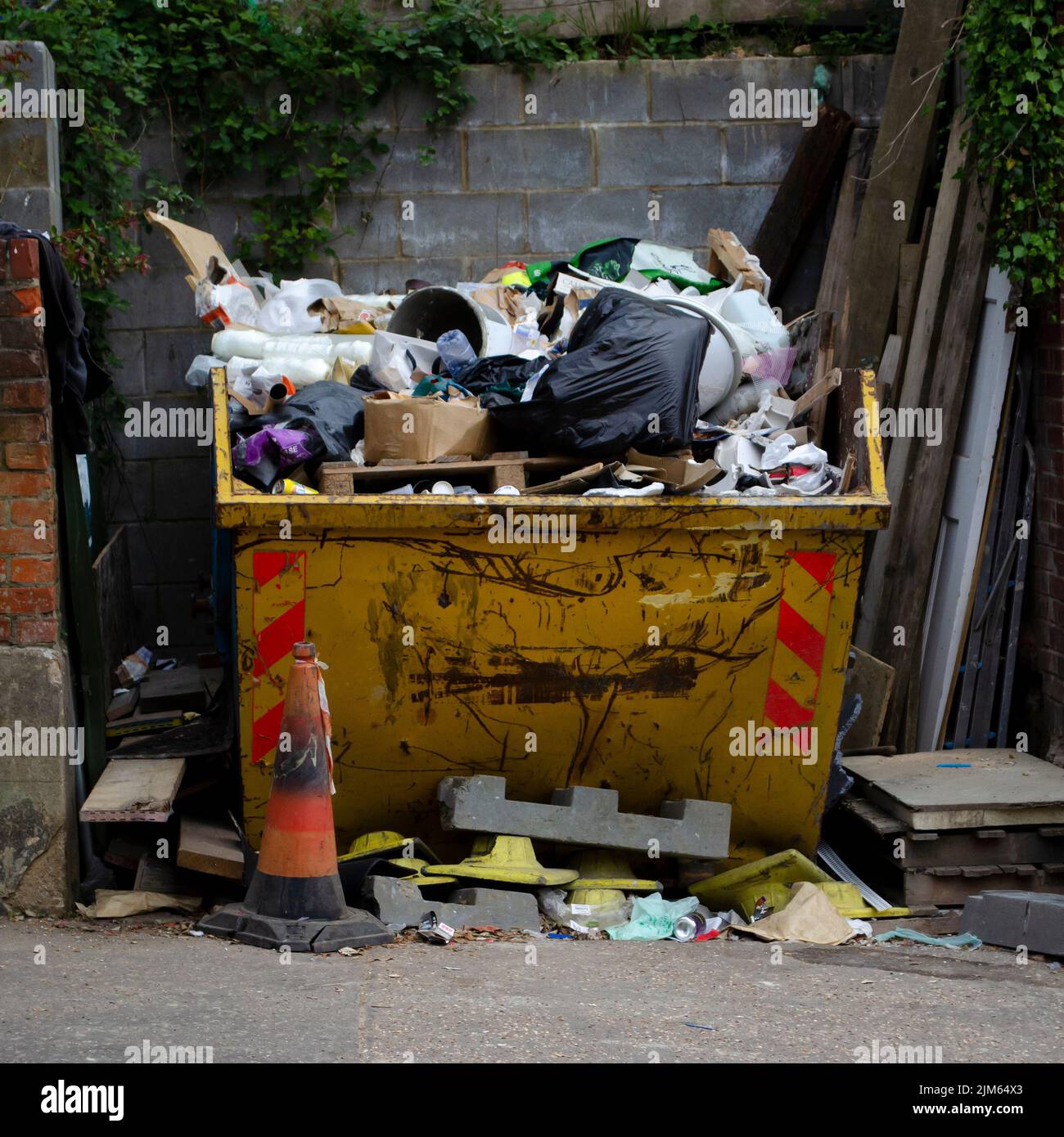 A full yellow rubbish skip full of trash from a building site. Wood and ...