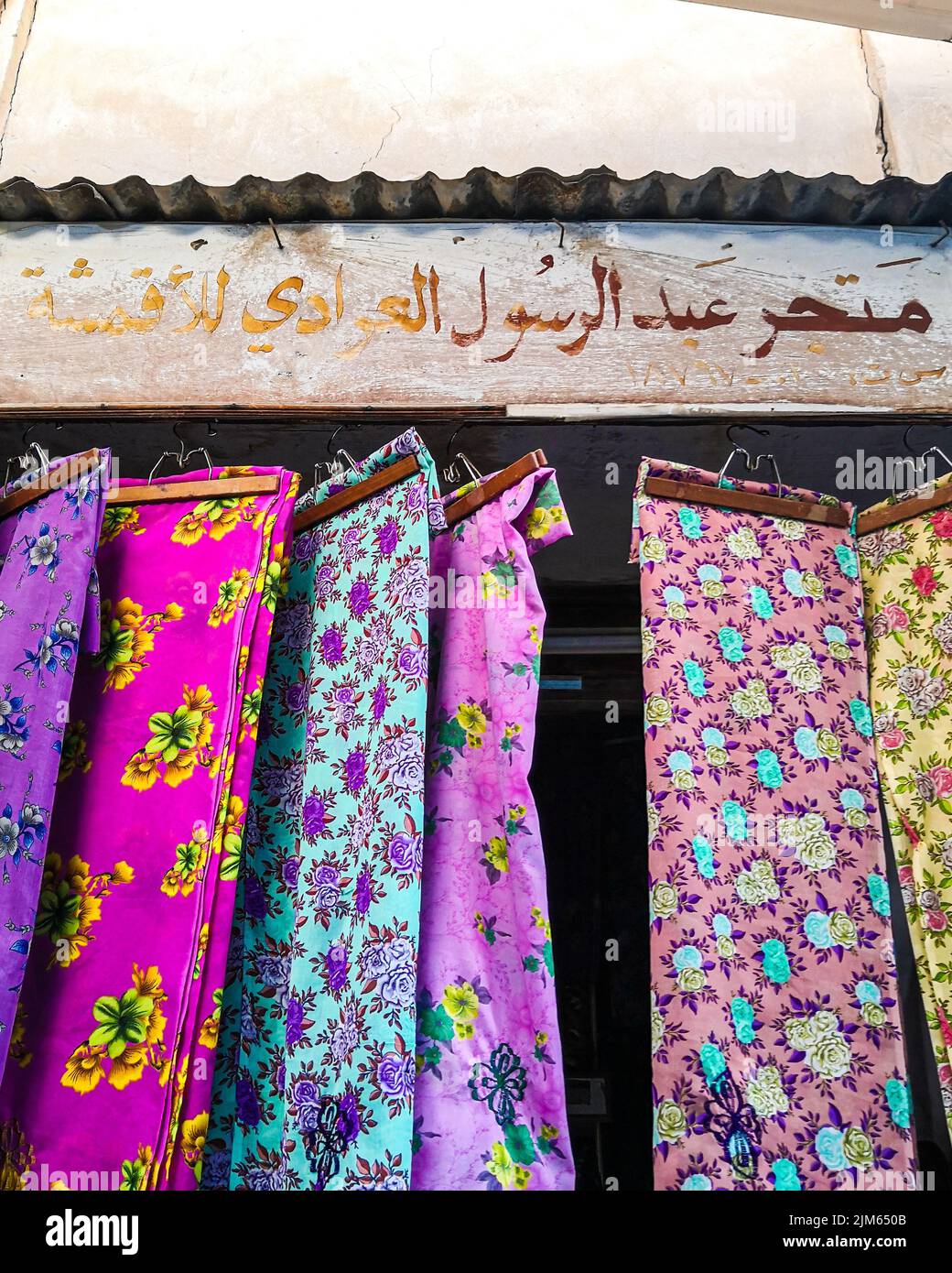 Fabrics hanging in a trader's store in Manama Souq, Manama, Bahrain ...
