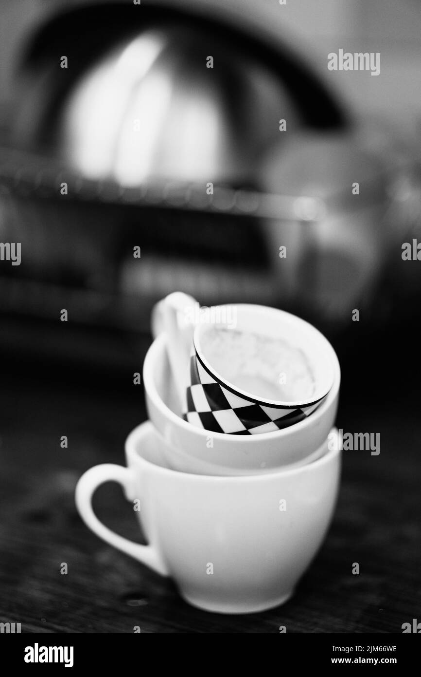 A grayscale shallow focus of white marble cups and a white and black ...