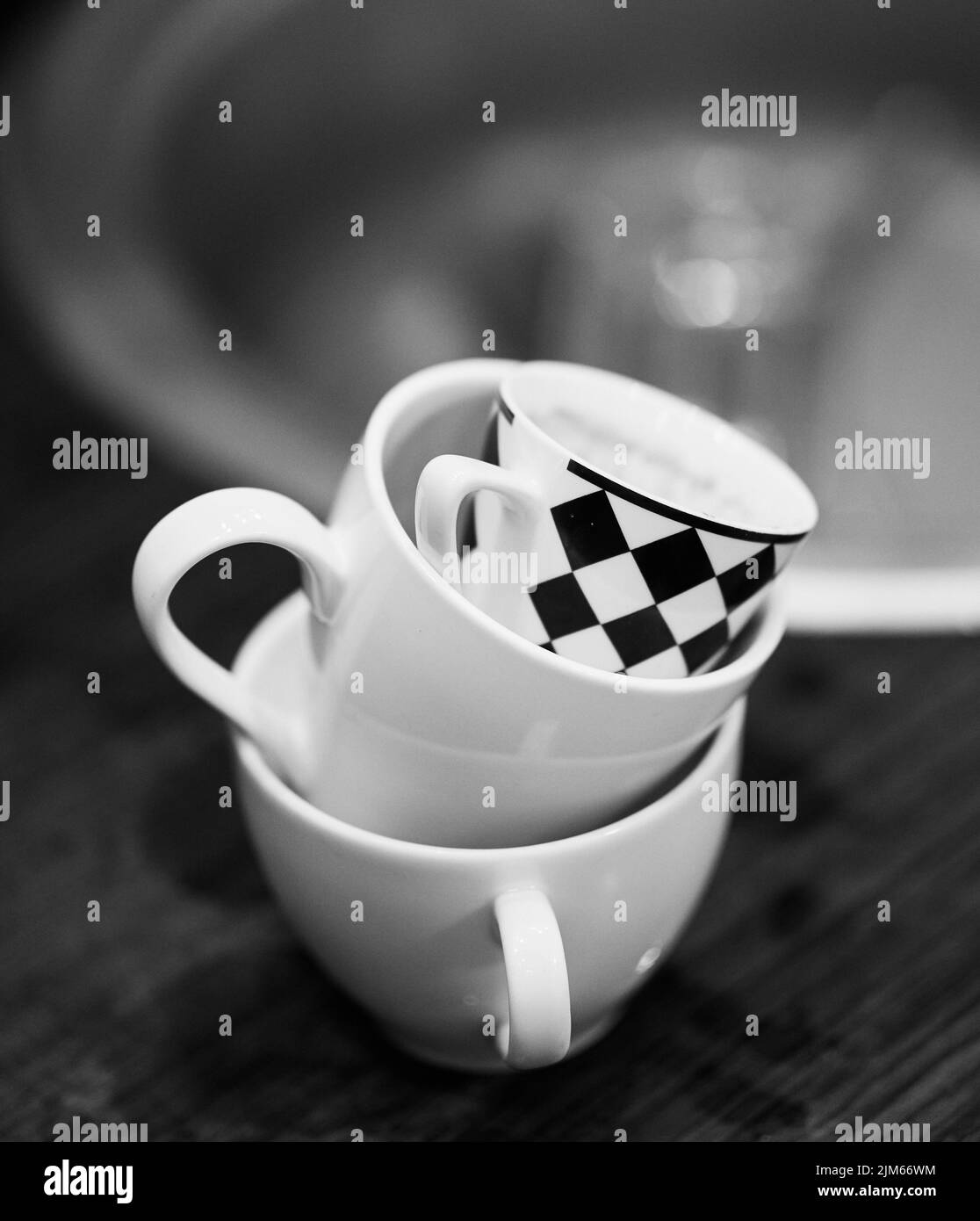 A grayscale shallow focus of white marble cups and a white and black ...