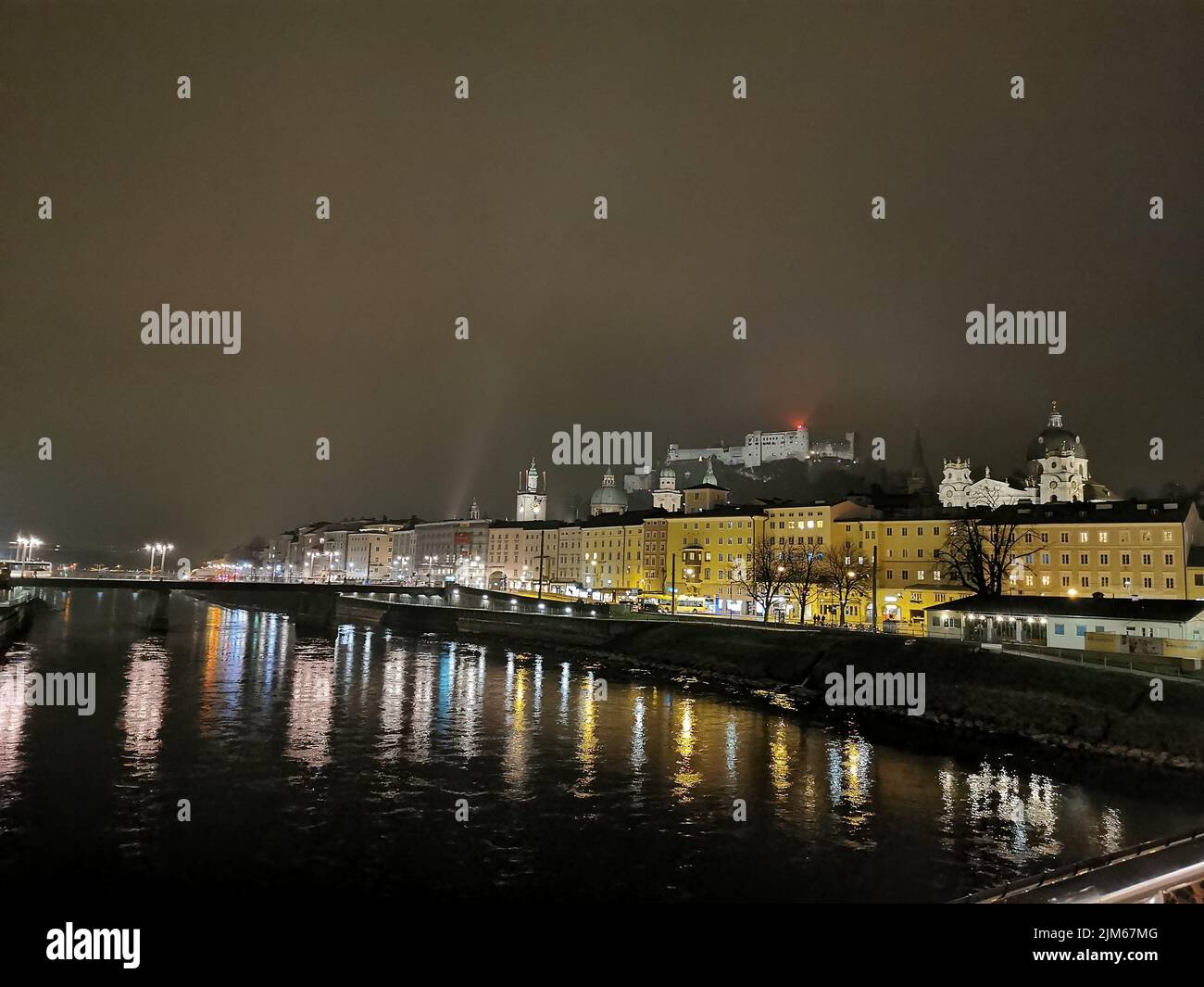 A scenic view of coastline buildings with illuminated lights reflected ...